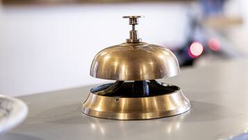 Um sino de hotel de latão com puxador mecânico, sobre uma superfície metálica.