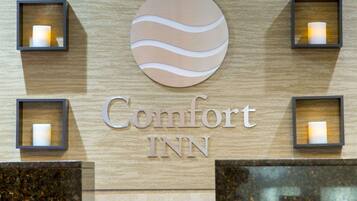 Placa da Comfort Inn com quatro luminárias fixadas na parede e o logotipo central.