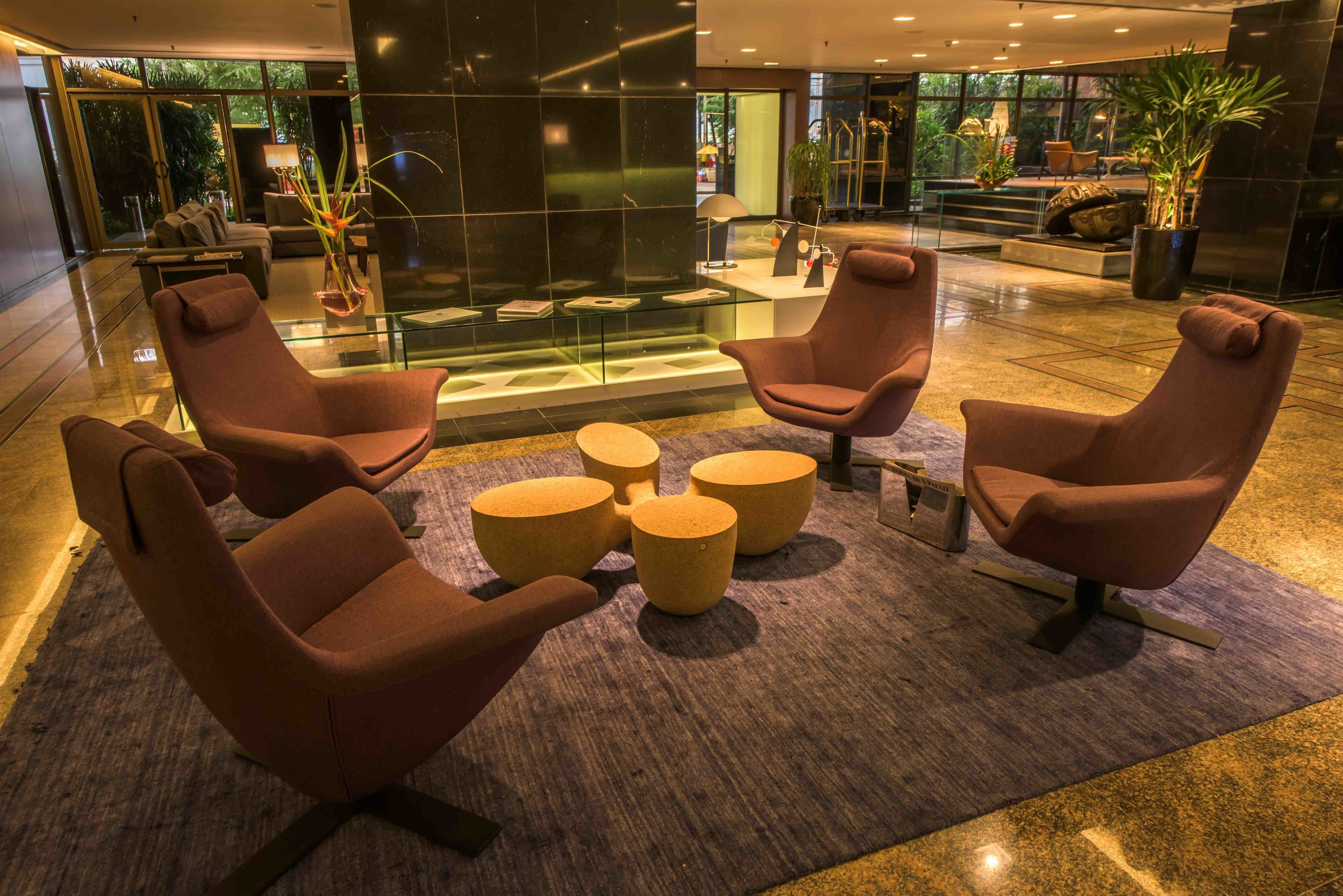 Um hall moderno com uma mesa de recepção de vidro, assentos confortáveis e um elemento decorativo central com água.