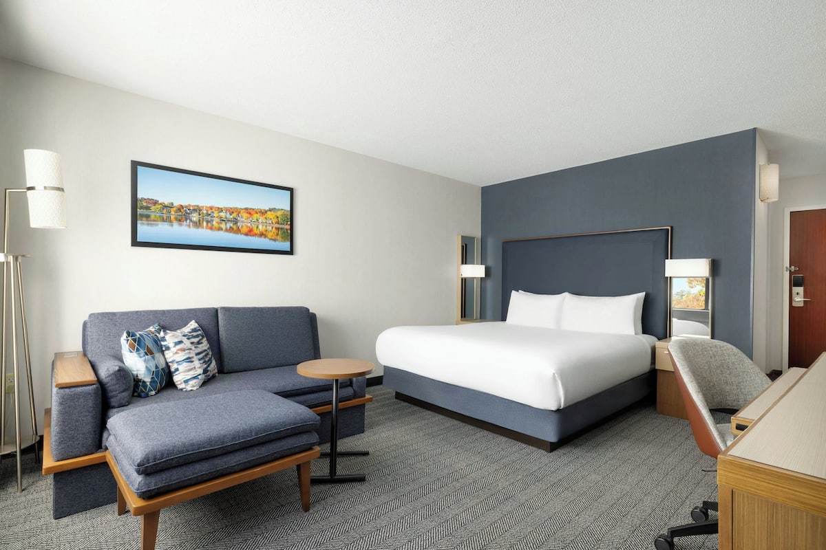 Quarto de hotel com cama, sofá, escrivaninha e cadeira.
