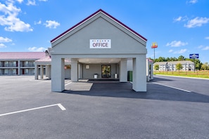 Um edifício com uma placa indicando 'OFFICE' na entrada, um estacionamento e um letreiro do McDonald's ao fundo.