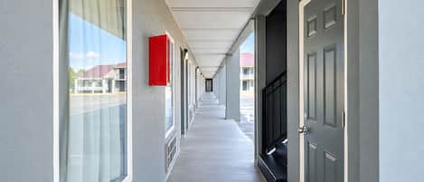 Corredor com teto, porta e janela com cortinas.