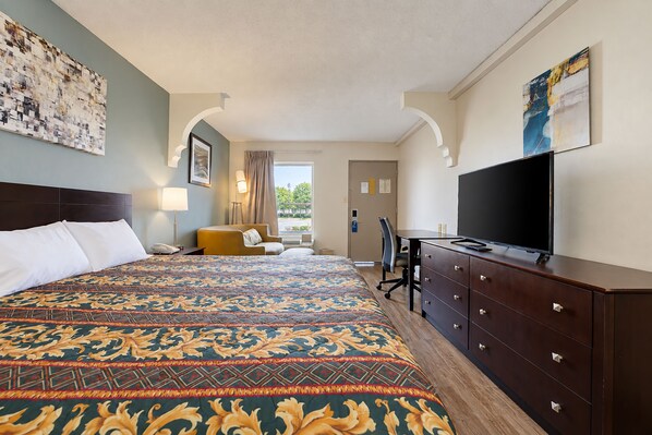 Quarto de hotel com cama grande, escrivaninha, televisão e vista para o exterior.