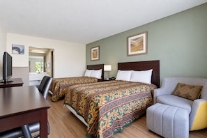 Quarto de hotel com duas camas, uma mesa, uma cadeira e uma televisão.
