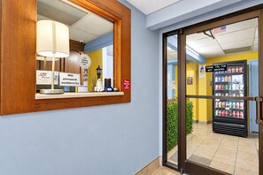 Uma área de recepção com espelho emoldurado em madeira, luminária e placa indicando acesso à rede WiFi.