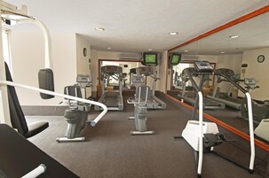 Uma academia com esteiras, elípticos e equipamentos de musculação.