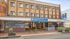 Um hotel Comfort Inn com fachada de tijolos, uma área de recepção e um restaurante visível chamado "The GRILL".