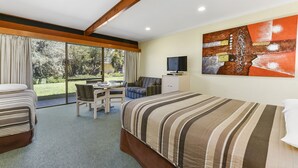 Quarto de hotel com uma cama grande, uma escrivaninha, uma cadeira, uma televisão e um quadro na parede.