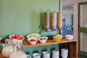 Uma mesa de buffet com diversos alimentos e dispensadores de bebidas.