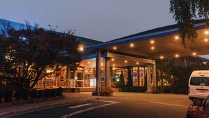 Entrada de hotel com galeria coberta, colunas e um banco.
