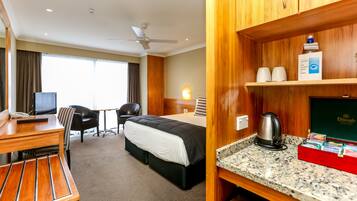 Quarto de hotel com cama, escrivaninha, cadeira e cafeteira.