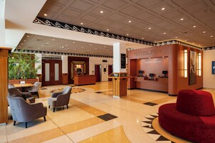 Um saguão de hotel com balcão de recepção, área de estar e balcão de check-in.