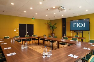 Sala de conferência com uma mesa comprida, cadeiras, projetor e uma tela exibindo 'FIGI'.