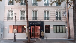 Um edifício com fachada identificada por 'JOLI MOME' e entrada visível.