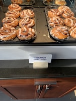 Uma variedade de cinnamon rolls em bandejas.