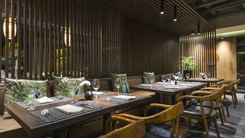 Um restaurante com mobiliário de madeira, almofadas com tema de pavão e design de interiores moderno.