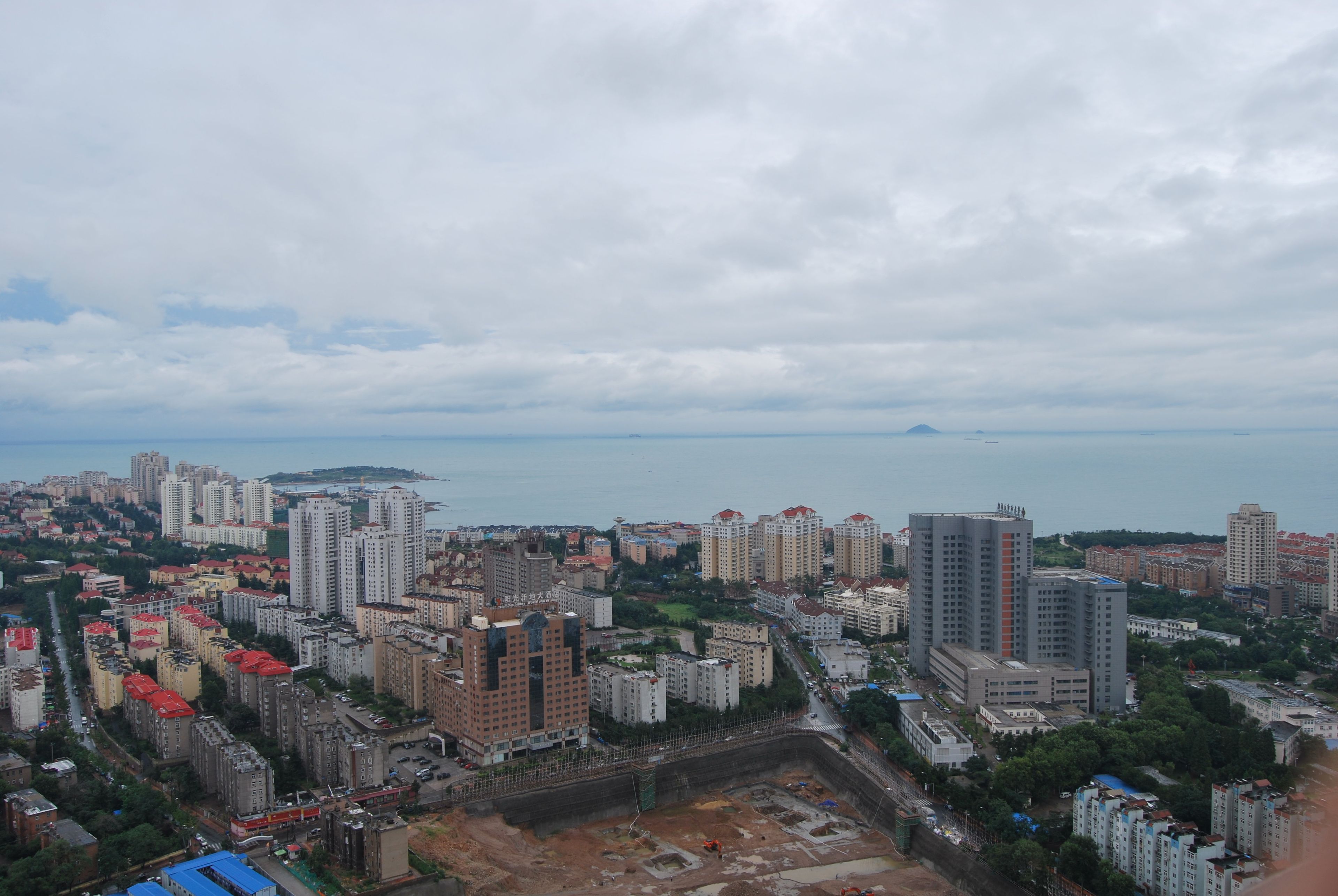 Paisagem urbana com edifícios altos, uma orla marítima e um canteiro de obras.