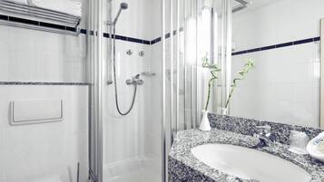 Uma casa de banho moderna com chuveiro em cabine de vidro, lavatório com bancada de granito e sanita branca.