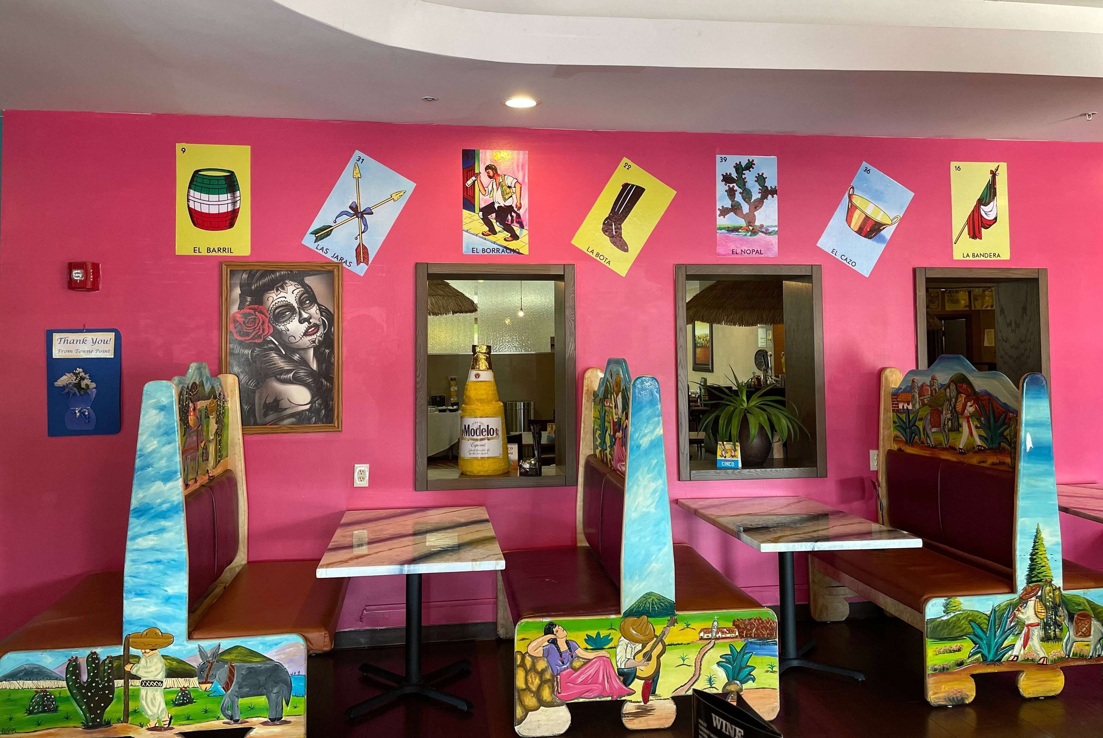 Um quarto vibrante com paredes cor-de-rosa, móveis de madeira e diversas decorações culturais.