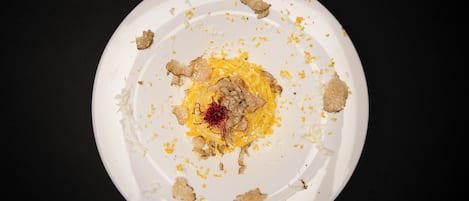 Um prato branco com restos de comida, incluindo macarrão e carne, sobre um fundo escuro.