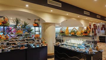 Uma área de buffet com diversos alimentos e uma decoração de plantas.