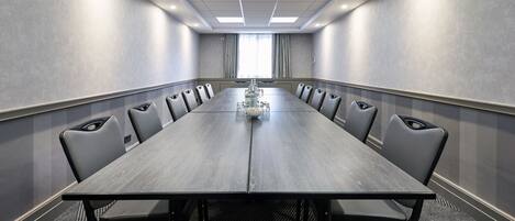 Uma sala de conferências com uma mesa comprida, cadeiras e uma pequena mesa com petiscos.