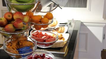 Buffet com diversos alimentos, incluindo frutas, doces e chocolates.