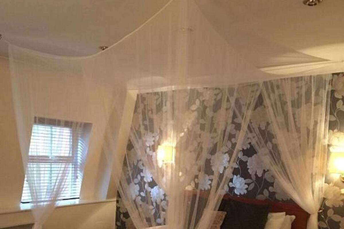 Um quarto com uma cama de dossel, um sofá e uma mesa de cabeceira.