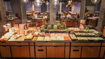 Uma área de buffet com diversas opções de comida, mesas e luminárias pendentes.