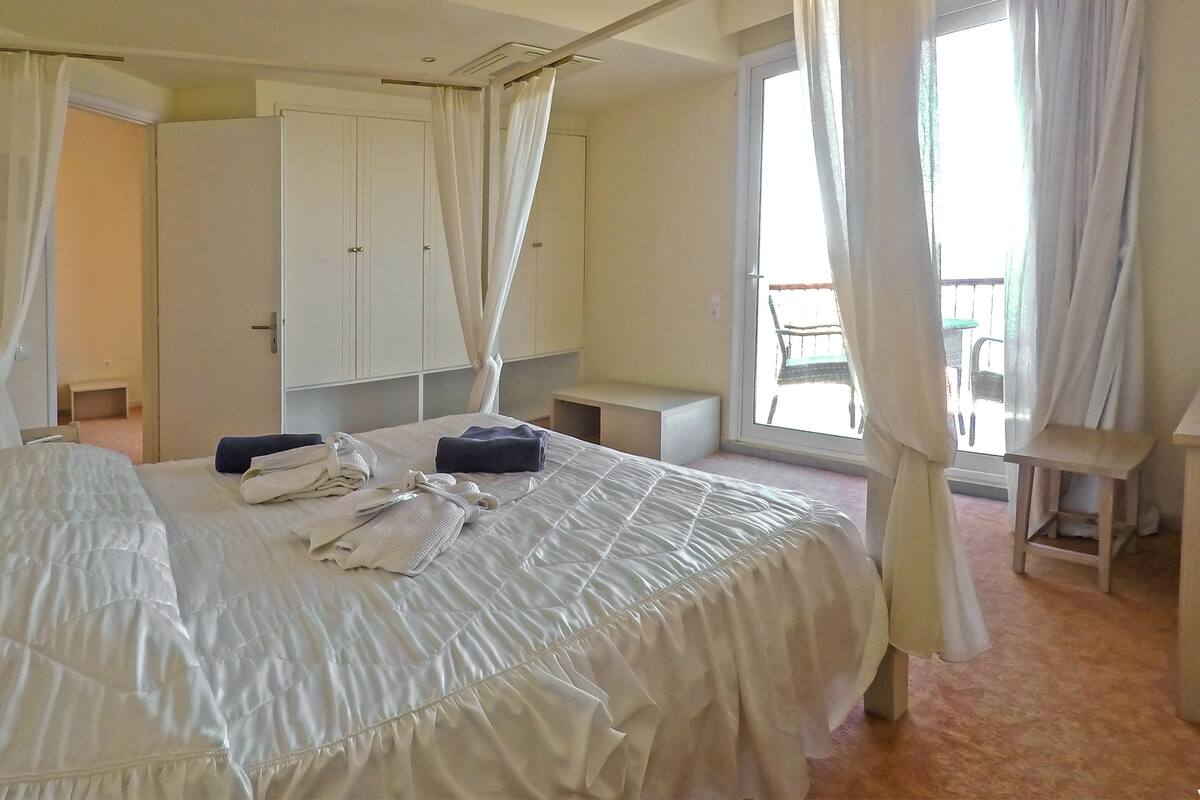 Uma cama bem arrumada com roupa de cama branca, um cabeceiro de madeira e uma pequena mesa de cabeceira.