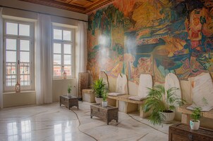 Um quarto amplo com um grande mural, um banco e plantas em vasos.