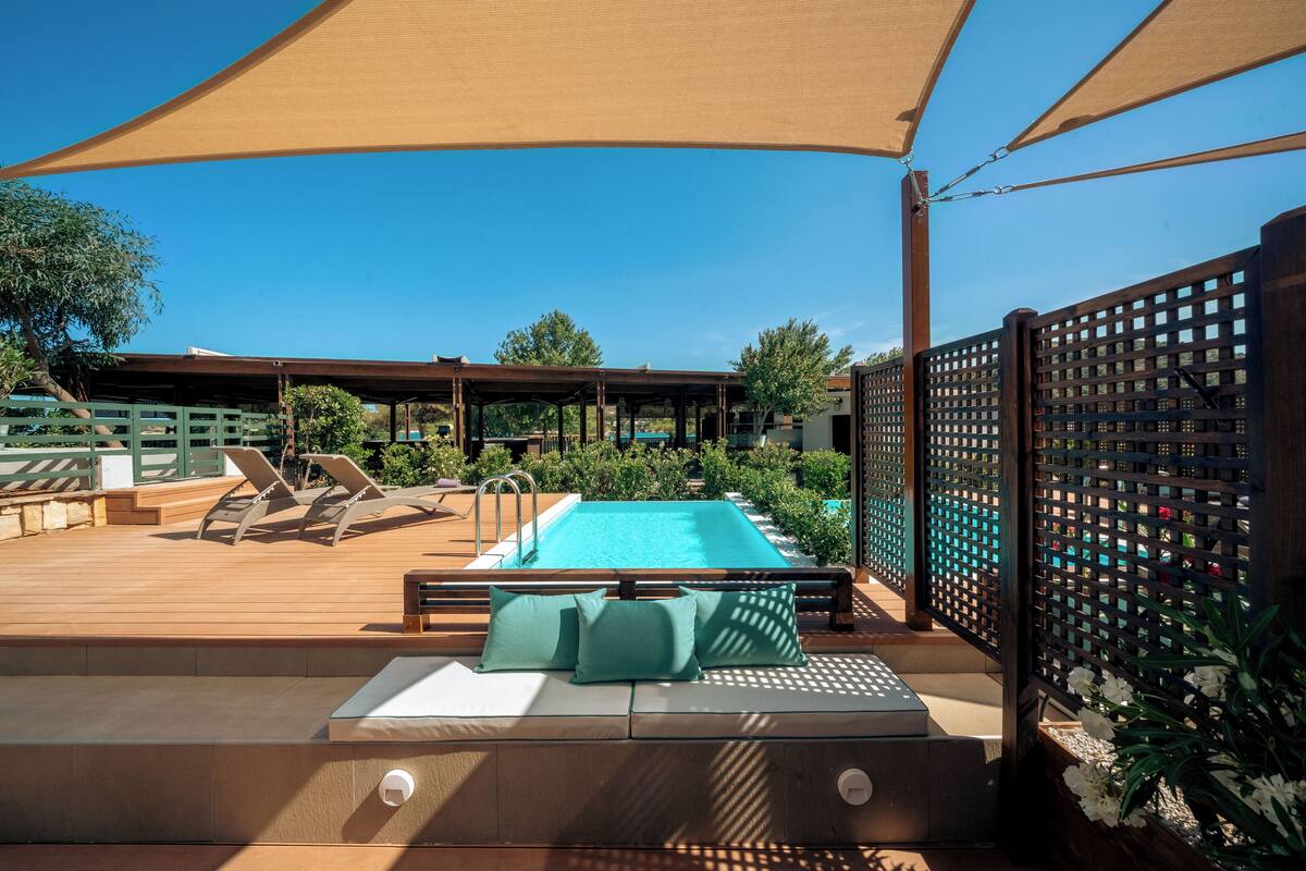 Uma área de piscina com espreguiçadeiras, piscina e um espaço de estar coberto.