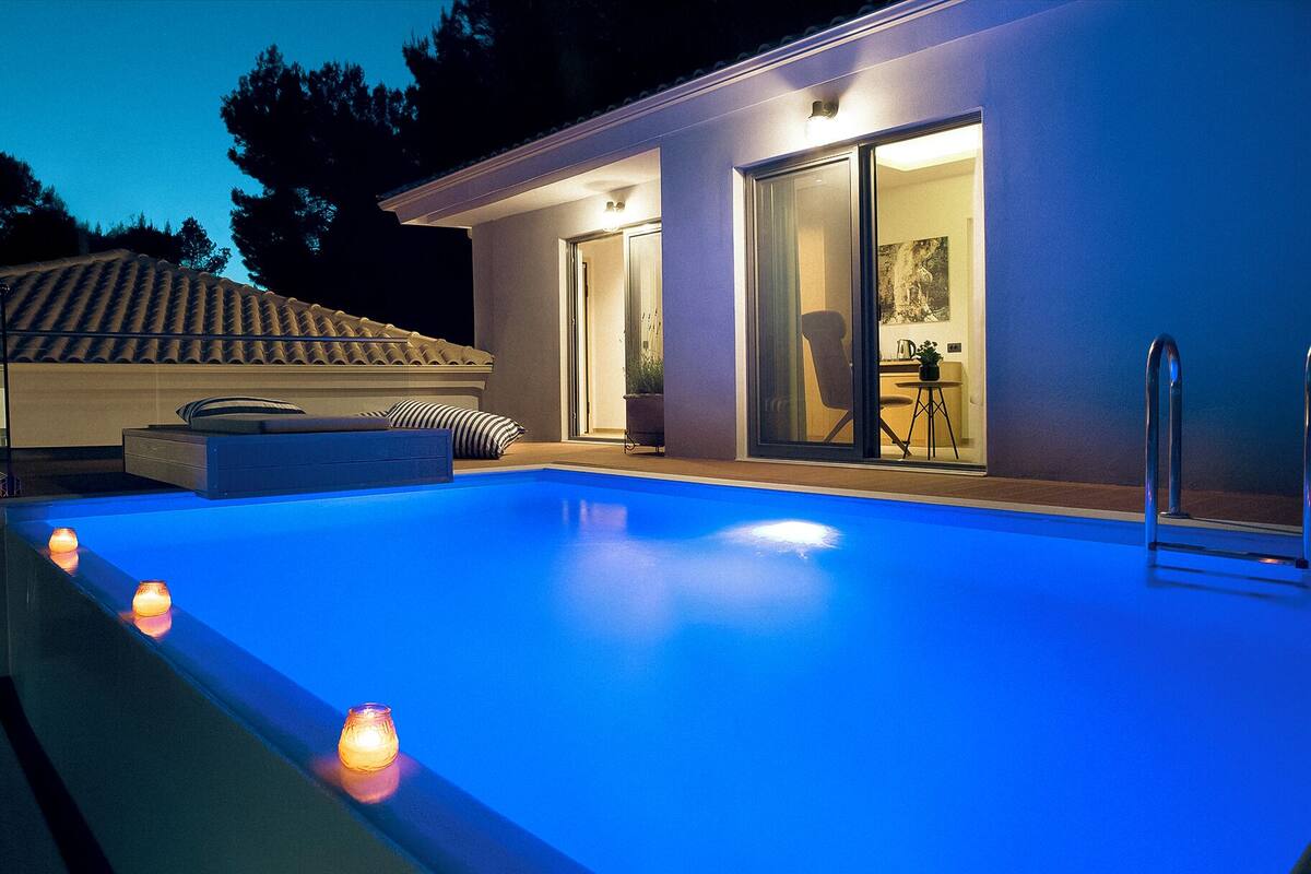 Uma casa moderna com piscina, um pátio com mobiliário e uma porta de correr de vidro que dá para o interior.