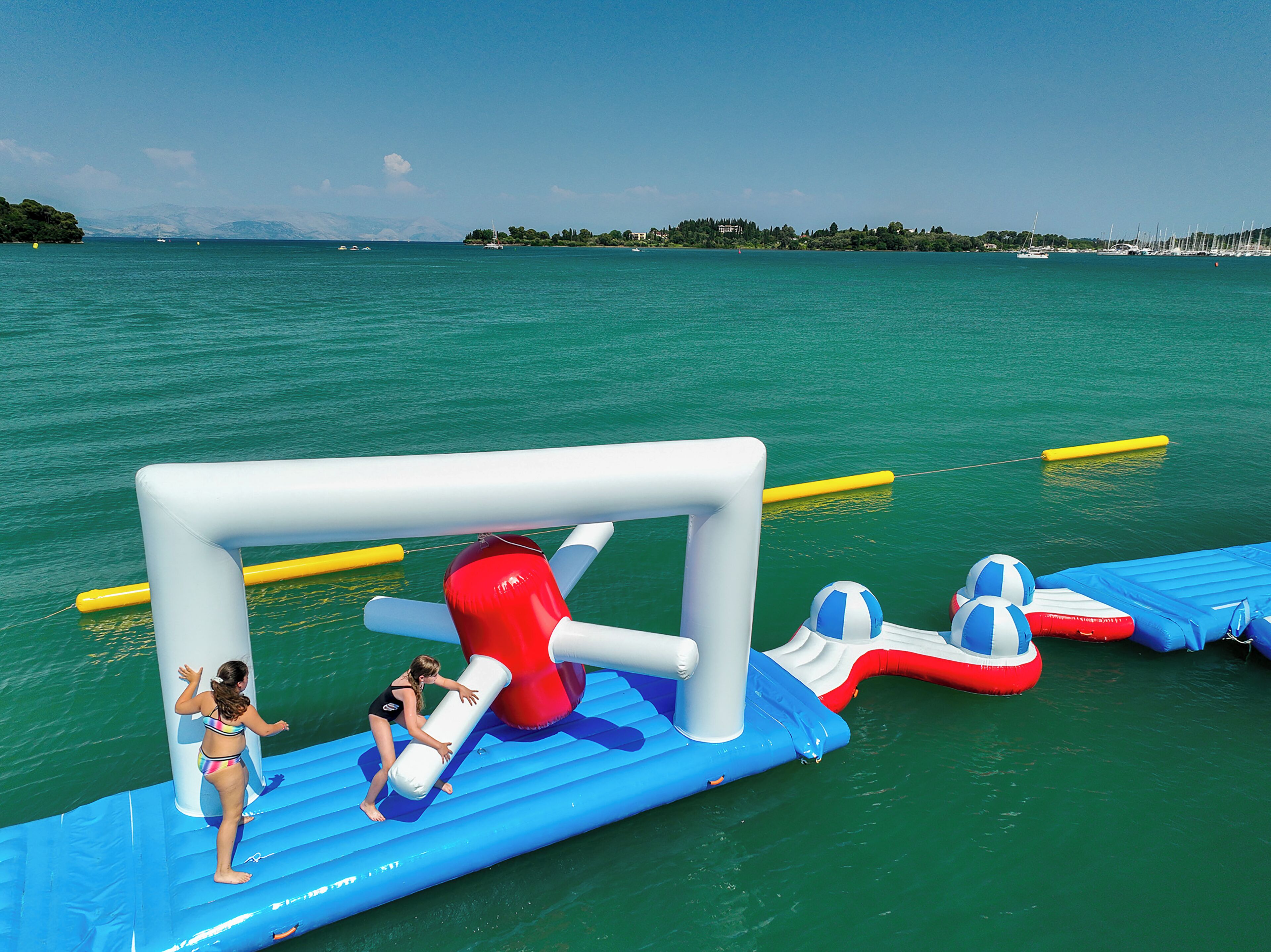 Parque aquático com estruturas infláveis e vista clara para o mar.