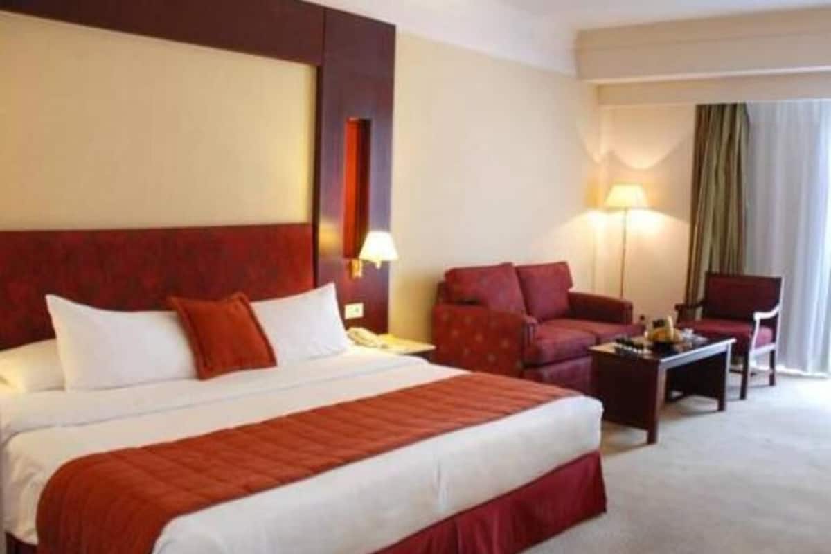 Quarto de hotel com uma cama grande, uma escrivaninha, uma cadeira e um sofá.
