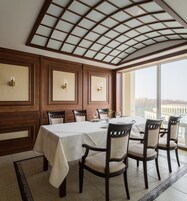 Uma sala de jantar com teto alto, amplas janelas e vista para a cidade.