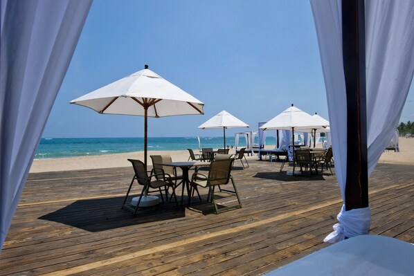 Na praia, areia branca, espreguiçadeiras, guarda-sóis