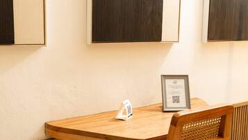 Uma mesa de jantar de madeira com um certificado emoldurado, uma cadeira com encosto trançado e uma parede com arte abstrata.