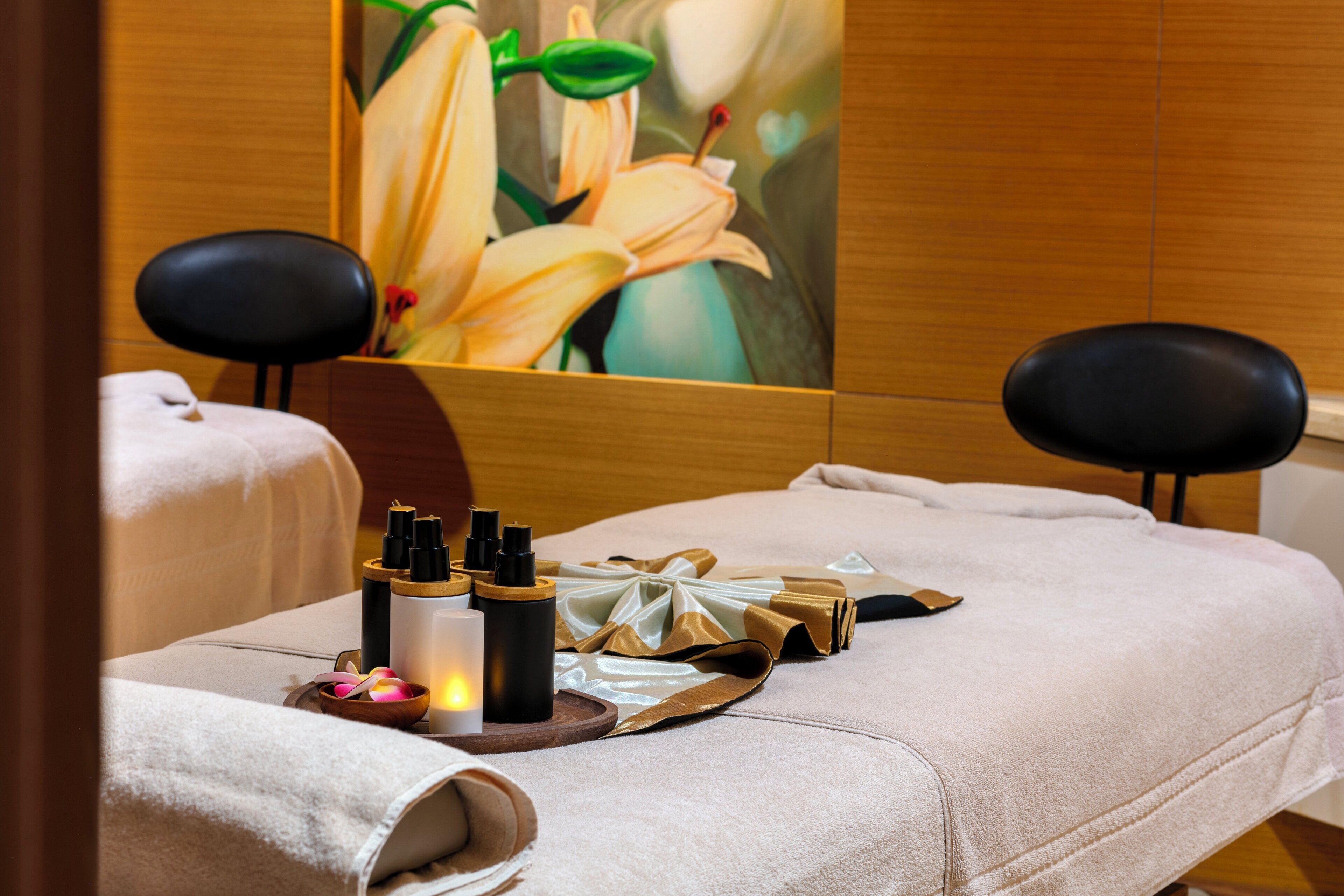 Um espaço de tratamentos de spa com mesa de massagem, toalhas, velas e óleos essenciais.