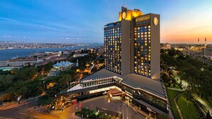 Um hotel moderno com uma torre imponente, um hall espaçoso e vista para a paisagem urbana e o mar.