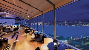 Um bar moderno com vista para a cidade à noite.