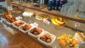 Buffet com diversos alimentos, incluindo doces, tortas e uma saladeira de frutas.