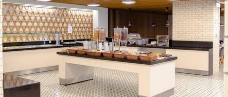 Uma área de café da manhã moderna com um balcão de serviço central, piso estampado e teto de madeira.