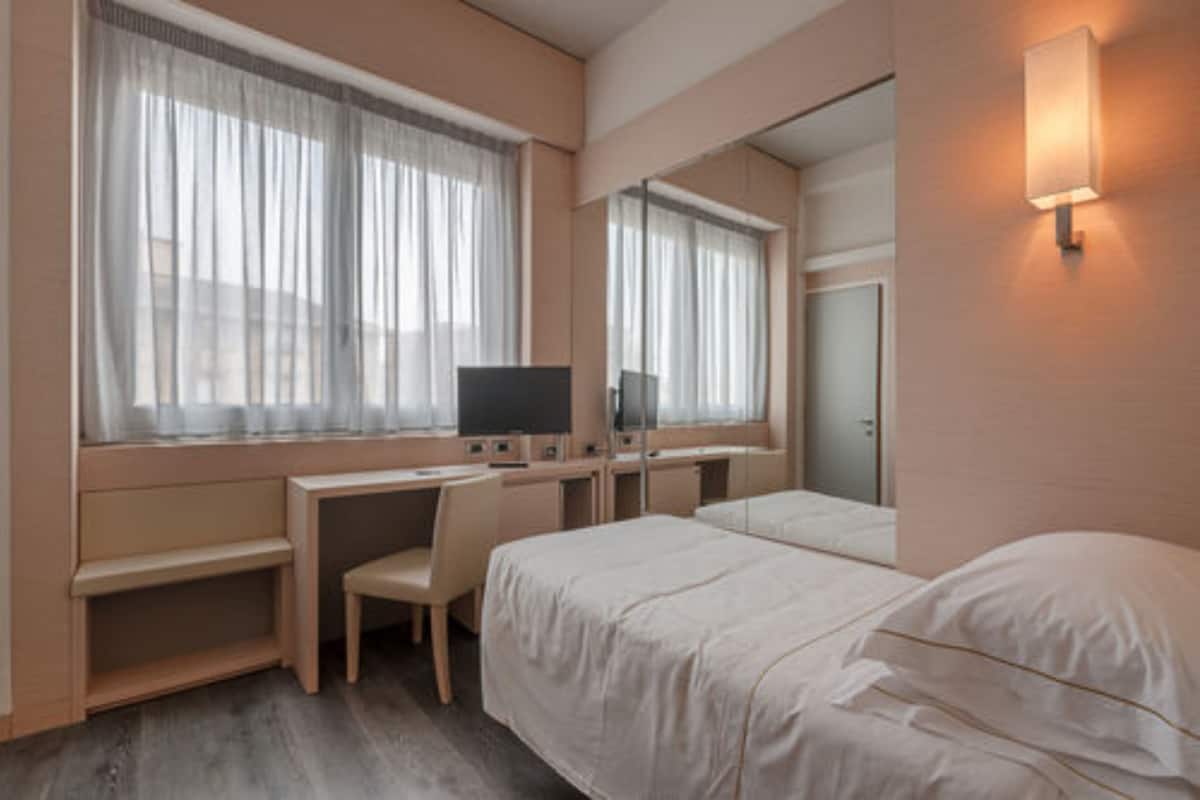Quarto de hotel com uma cama, uma mesa, uma cadeira e uma televisão.