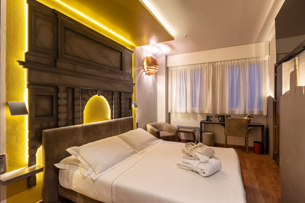Quarto de hotel moderno com uma cama grande, uma escrivaninha, uma cadeira e um banheiro.