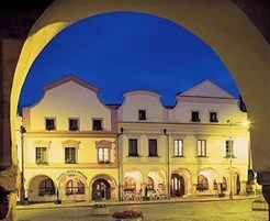 Um edifício grande, com vários andares, fachada simétrica, janelas em arco e entrada central.