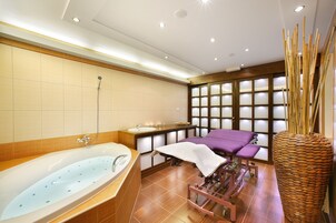Um banheiro moderno com uma banheira grande, um espelho sobre bancada de madeira, uma mesa de massagem e uma cesta grande de fibra.