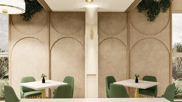 Interior de restaurante com uma coluna central, cadeiras verdes, mesas brancas e plantas decorativas.