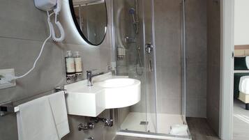Uma casa de banho moderna com uma grande pia, um bidé, uma cabine de duche de vidro e um espelho.