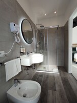 Uma casa de banho moderna com uma grande pia, um bidé, uma cabine de duche de vidro e um espelho.